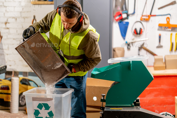 A waste recycling plant employee pours shredded plastic caps into ...