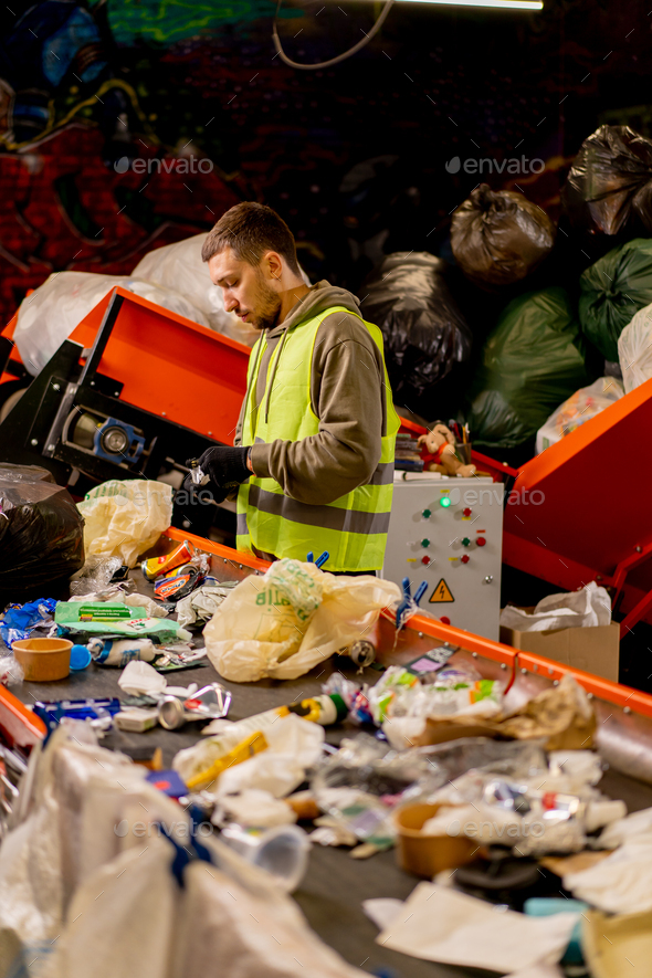 An employee in a uniform at a waste recycling station sorts and sorts ...