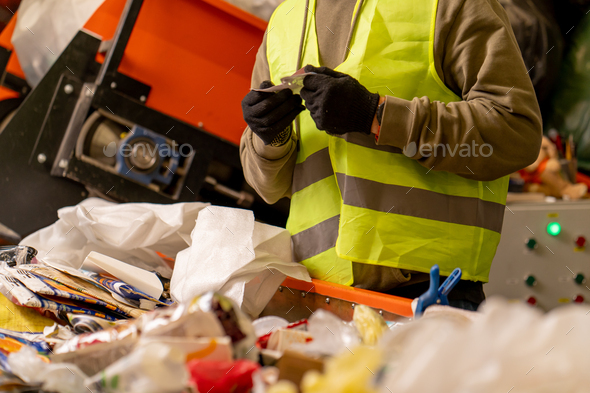 Hands in gloves of employee sort garbage into categories on a special ...