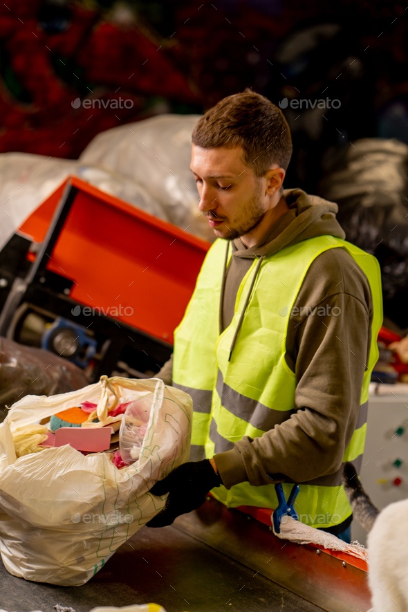 man in uniform working on a garbage distribution line and sorting waste ...
