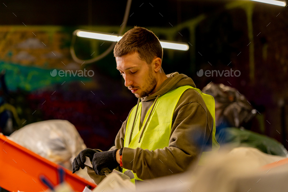man in uniform working on a garbage distribution line and sorting waste ...