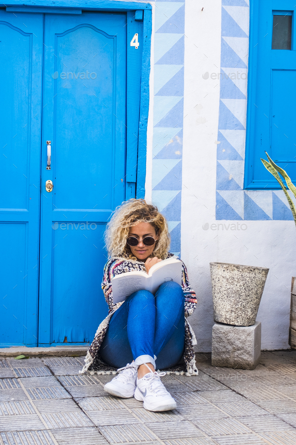 Chererful and relaxed beautiful woman sit down outside a colorful blue ...