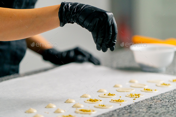 A gloved hand a confectioner sprinkles natural chocolate candies with ...