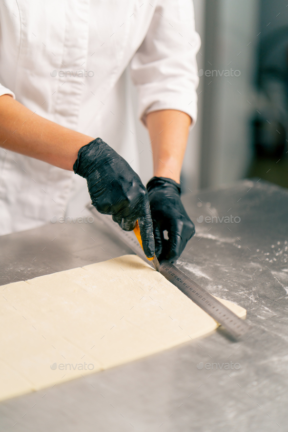 female chef's hands carefully kneading dough for preparing and baking ...