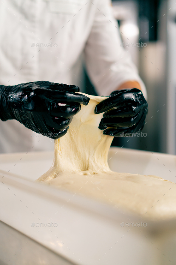 hands in gloves putting dough into a bread shape on a baking sheet for ...