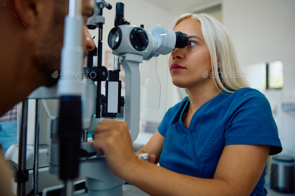 Female optometrist diagnosing eye and vision conditions of a patient at ...