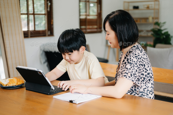 Homeschool Asian young little boy learning online and does homework by using computer Stock ...