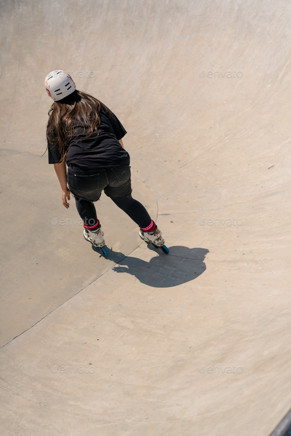 young skilled woman rollerblading and jumping on the ramp in the skate ...