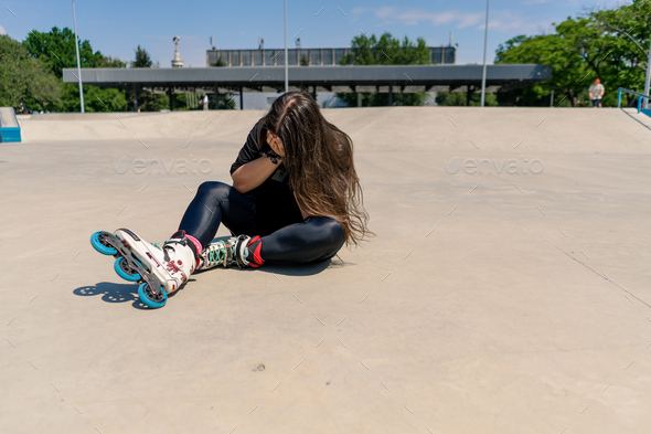 upset girl crying after falling on rollers on a roller rink ...