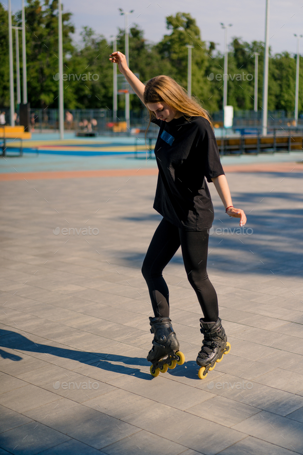 sporty girl practicing tricks on roller skates in park on city ...