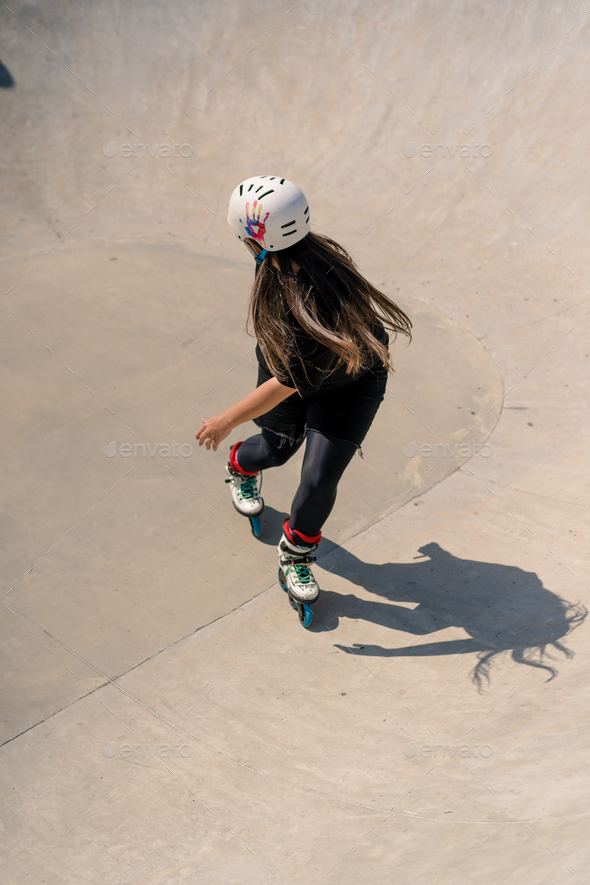 skilled woman rollerblading and jumping on the ramp in the skate park ...