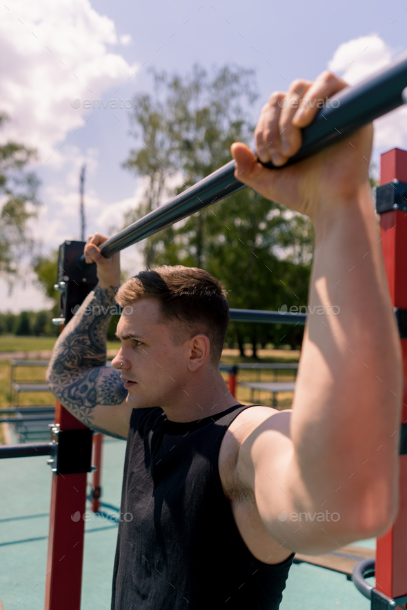 sportsman doing horizontal bar swings arms and shoulders push-ups on ...