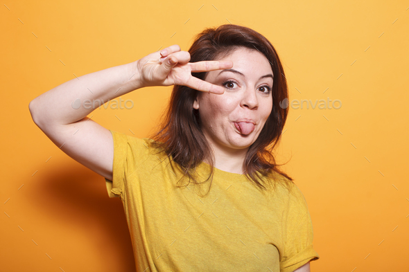 Female doing peace sign with tongue out Stock Photo by DC_Studio ...