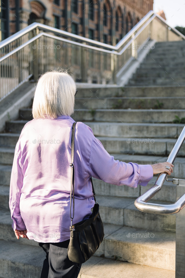 rear view of senior woman walking up stairs Stock Photo by Raul_Mellado