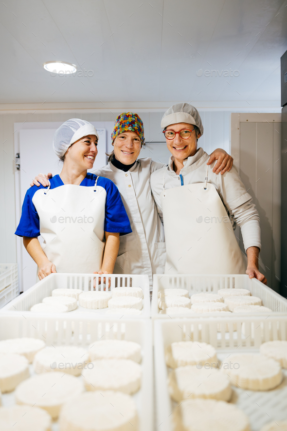 Smiling factory workers standing together near table full of containers ...