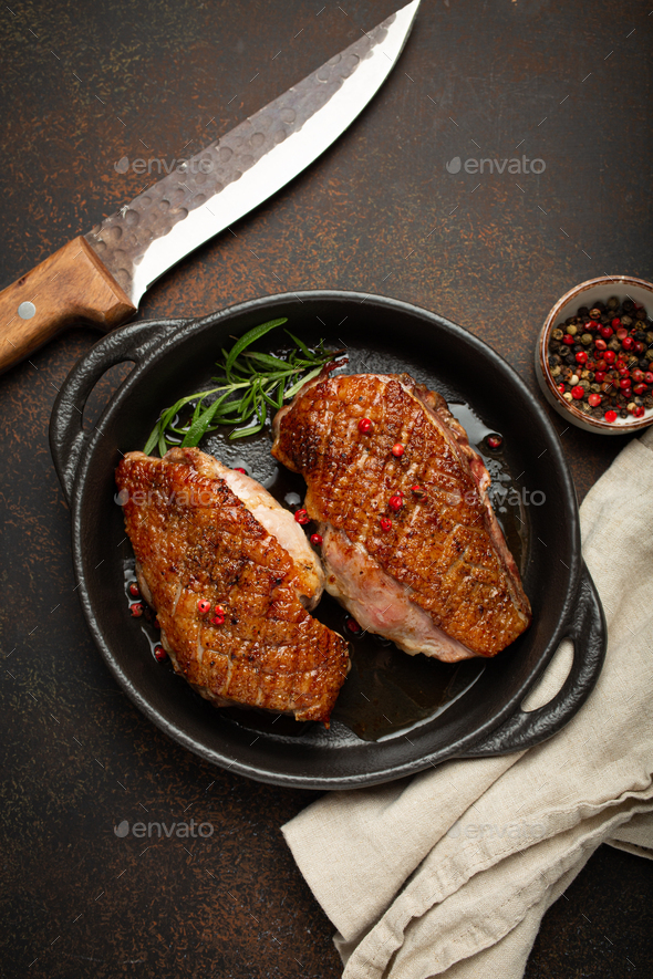 Two roasted duck breast fillets with crispy skin, with pepper and ...