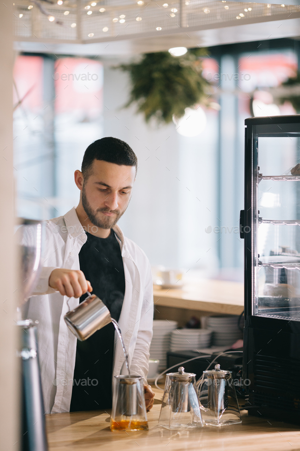 A young barista man prepares delicious teas in a modern cafe. Stock ...