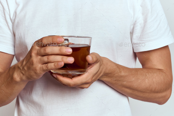 A man with a hot drink of tea in his hands in a white T-shirt on a ...