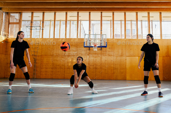 Interracial volleyball team in action playing volleyball on training ...