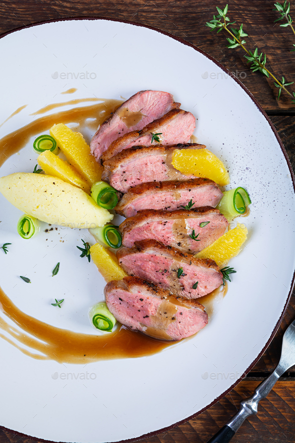 Roast duck fillet with mashed potato and orange sauce on wooden ...