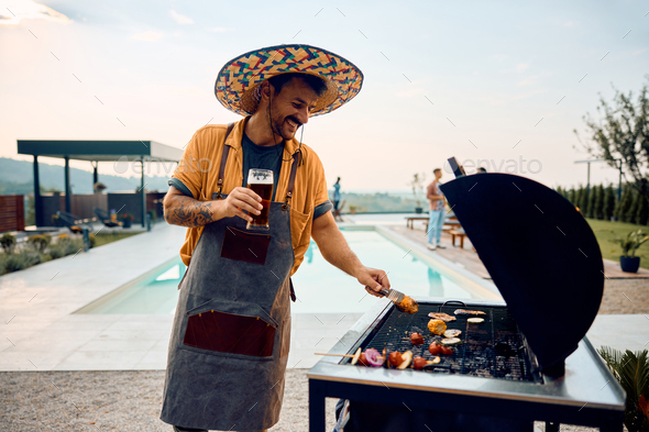 Happy man drinking beer while grilling food on a barbecue grill. Stock ...