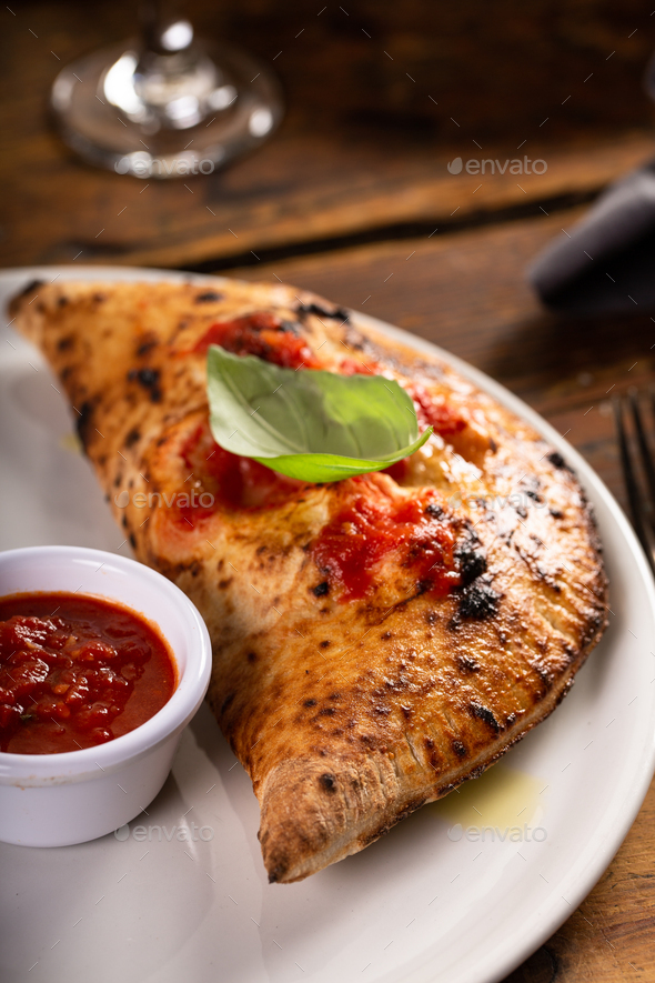Traditional Italian cheese calzone with marinara sauce Stock Photo by ...