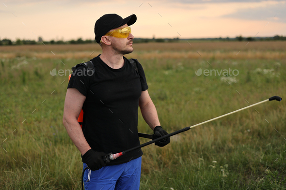 Farmer in protective glasses and gloves with mist sprayer treats potato ...