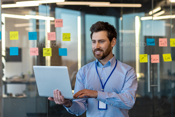 Smiling young man businessman, programmer and developer sitting inside ...
