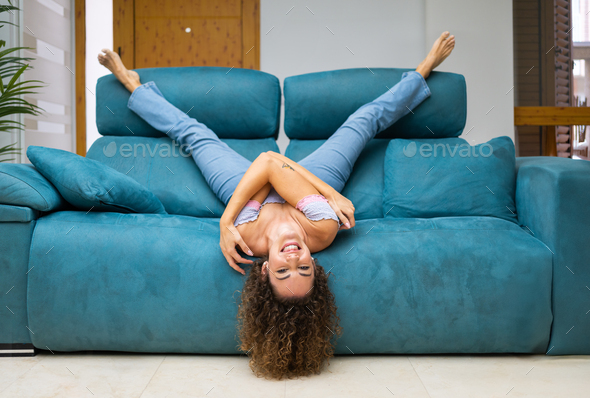 Cheerful woman lying upside down on sofa at home Stock Photo by javi_indy