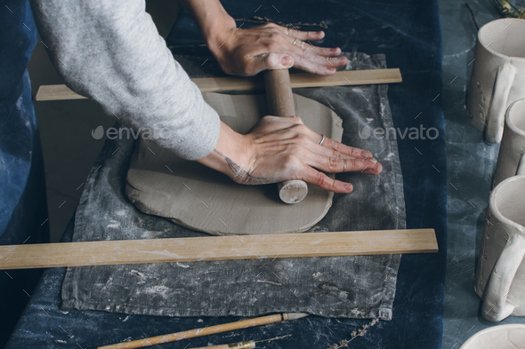 Person using rolling pin to flatten clay Stock Photo by ArtemVarnitsin