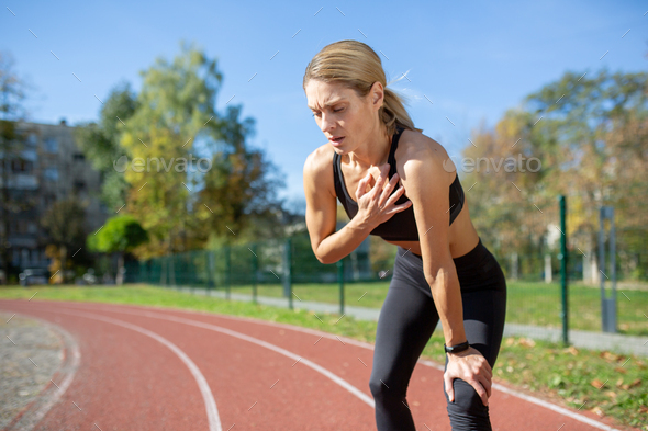 Female jogger catching her breath on track field after intense running ...