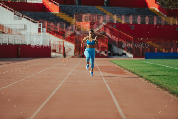 A fast female sprinter is sprinting towards camera on stadium. Stock ...