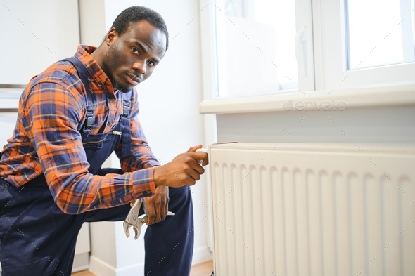 Repair heating radiator close-up. African man repairing radiator with ...