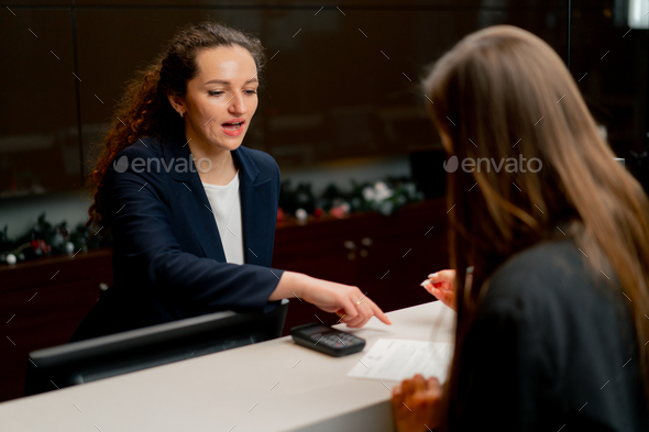 a smiling receptionist helping a guest to fill out a registration form ...