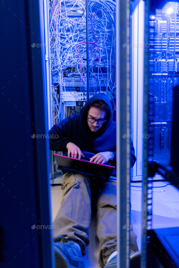 concentrated hooded hacker in data center hacking software system ...
