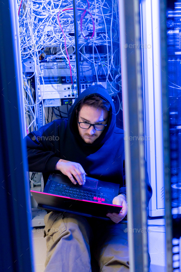 concentrated hooded hacker in data center hacking software system ...