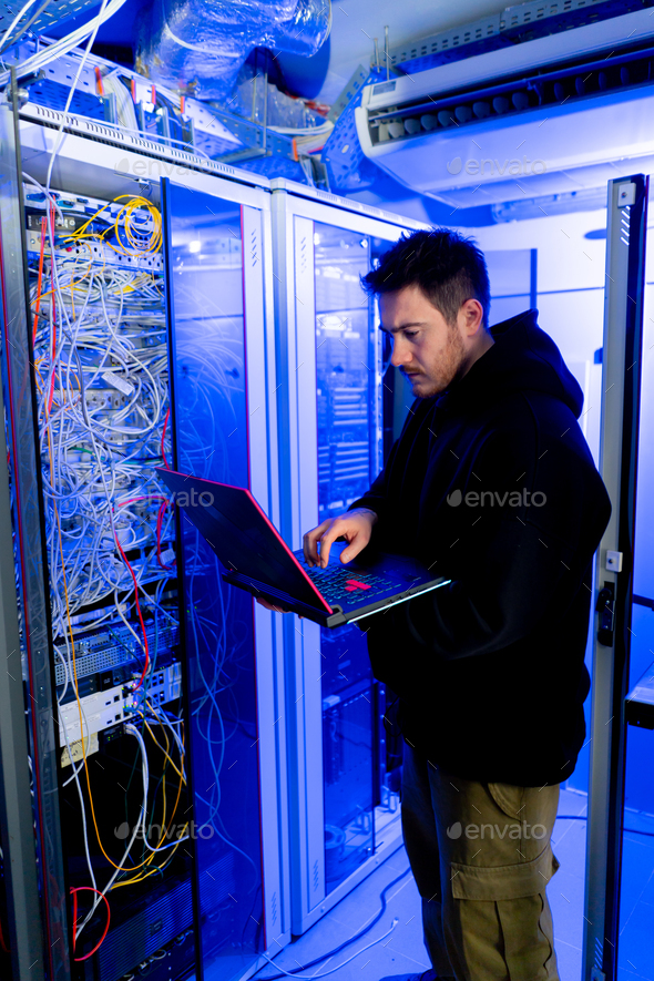 Focused Hacker In Data Center Hacking Software System Vulnerable Cyber Security Server Room