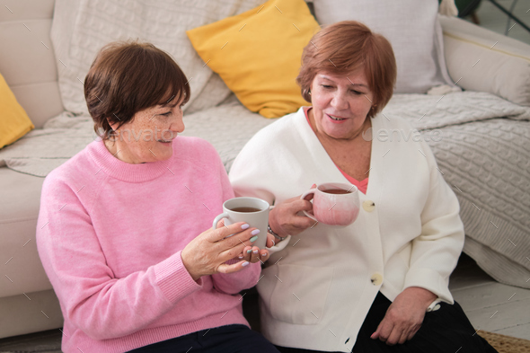 Senior tea party: Two smiling mature women relishing tea time and ...