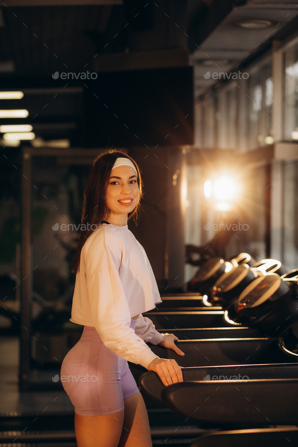 Side view of beautiful muscular woman running on treadmill. Stock Photo ...