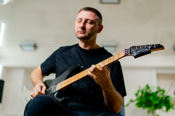 rock performer with electric guitar in recording studio playing musical ...