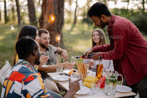 Meeting of multiracial group of friends eating dinner and drinking wine ...