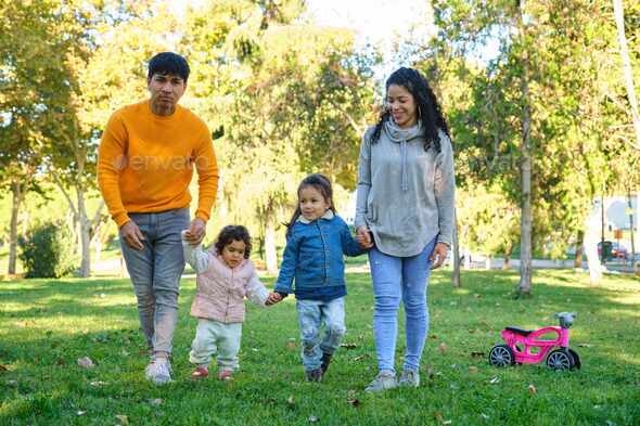 Latin happy family with two kids walking together in a park. Stock ...