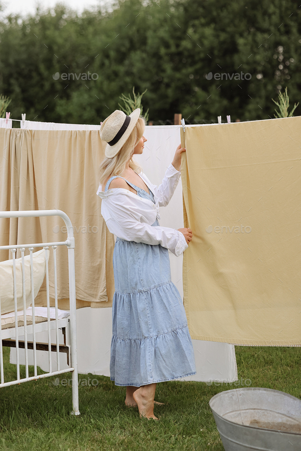 Caucasian woman hanging laundry outdoors. Front view. Stock Photo by ...