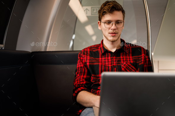 Man commuting to work or school by a train or a subway while using a ...