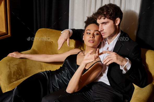 young multicultural couple in elegant attire touching each others ...