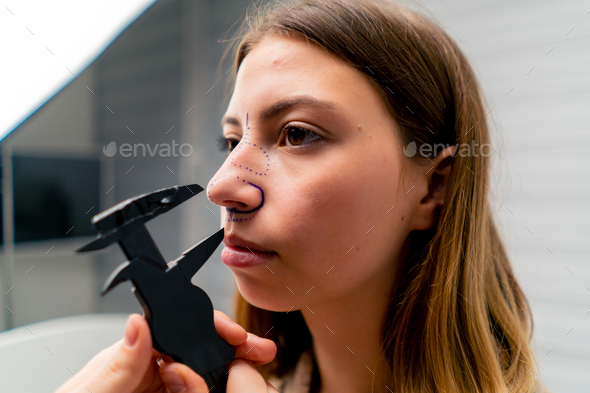 close-up doctor holds an ENT instrument to measure the nose a female ...