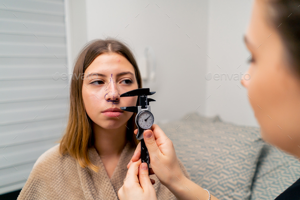 close-up doctor holds an ENT instrument to measure the nose a female ...
