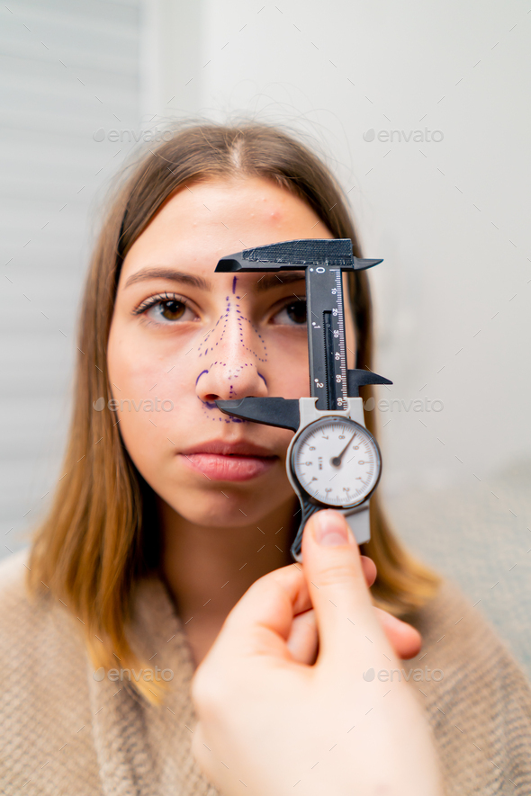 close-up doctor holds an ENT instrument to measure the nose a female ...