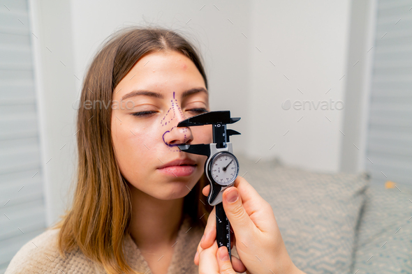 close-up doctor holds an ENT instrument to measure the nose a female ...