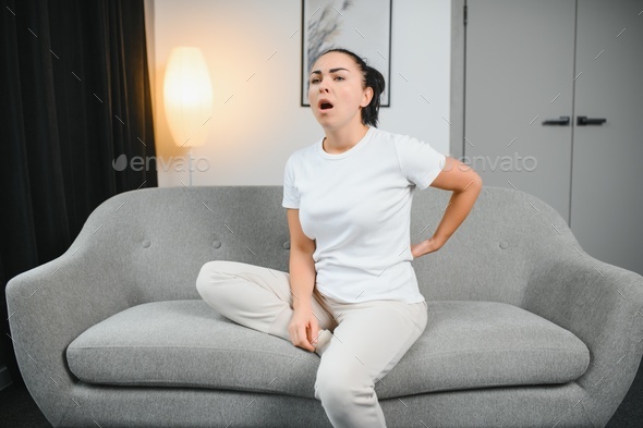 Sad young woman touching back feeling backache morning discomfort low ...